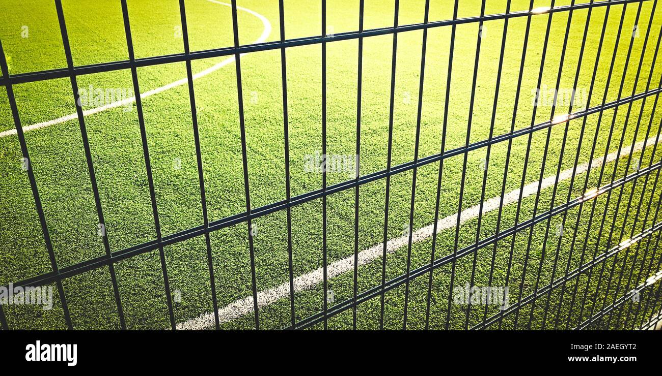 Sunny lawn field for playing minifootball behind the green fence mesh ...