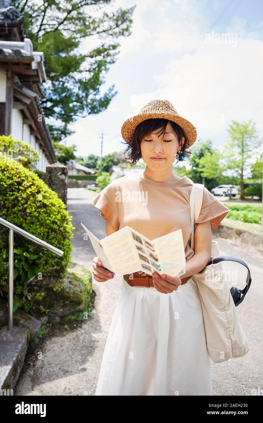 Japanese woman wearing hat and holding map standing outside Buddhist ...