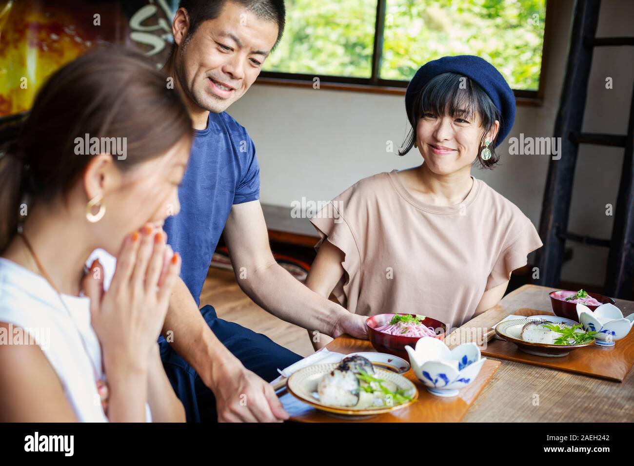 Waiter serving two Japanese women sitting at a table in a Japanese ...
