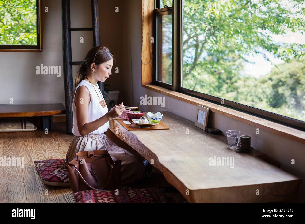 Japanese woman sitting at a table in a Japanese restaurant, eating ...