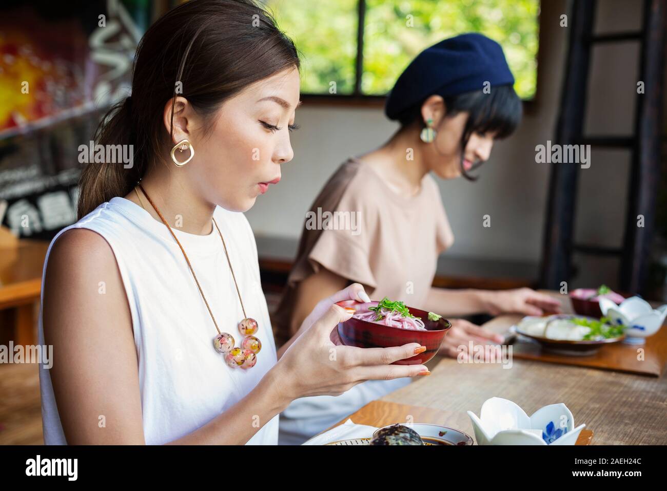 Two Japanese women sitting at a table in a Japanese restaurant, eating ...