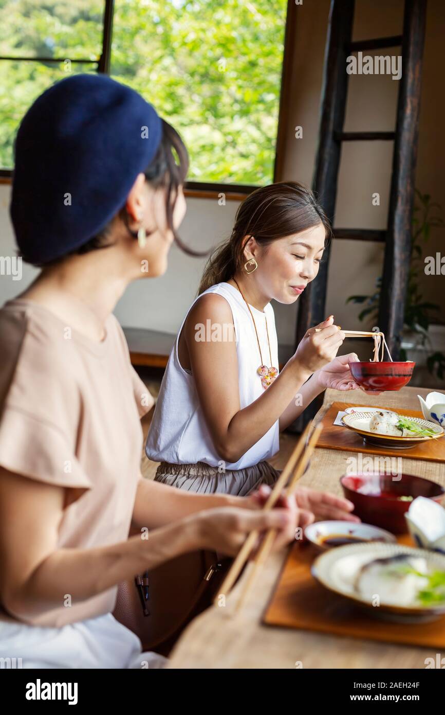 Two Japanese women sitting at a table in a Japanese restaurant, eating ...