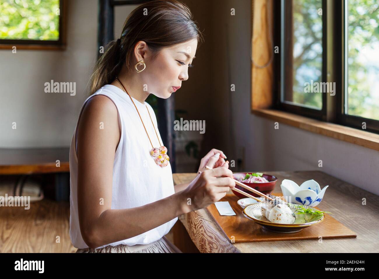 Japanese woman sitting at a table in a Japanese restaurant, eating ...