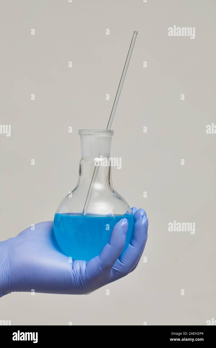 Close-up of male hands in gloves holding flask with blue water during ...