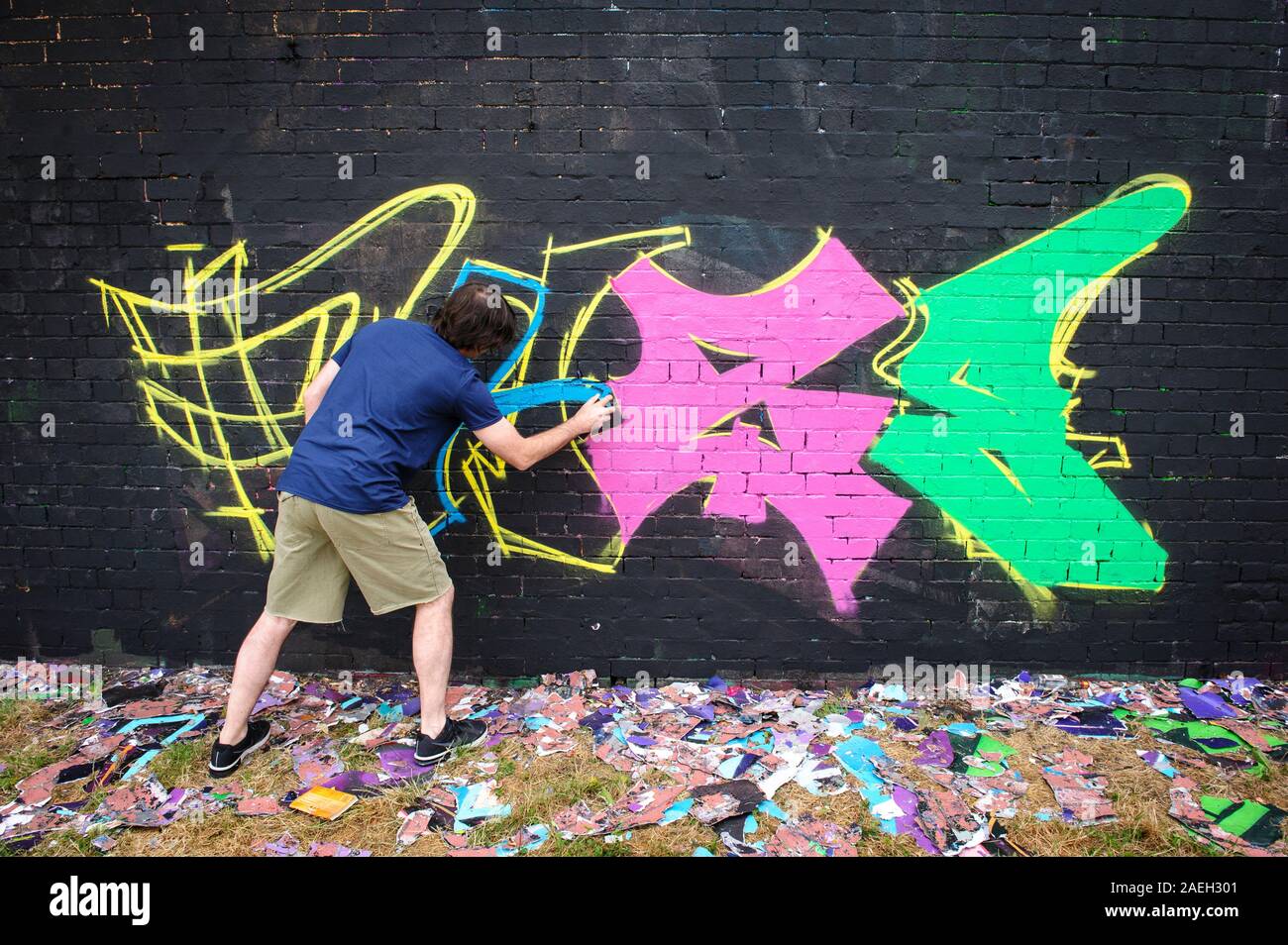 Male graffiti artist staying his own design onto a black wall Stock ...