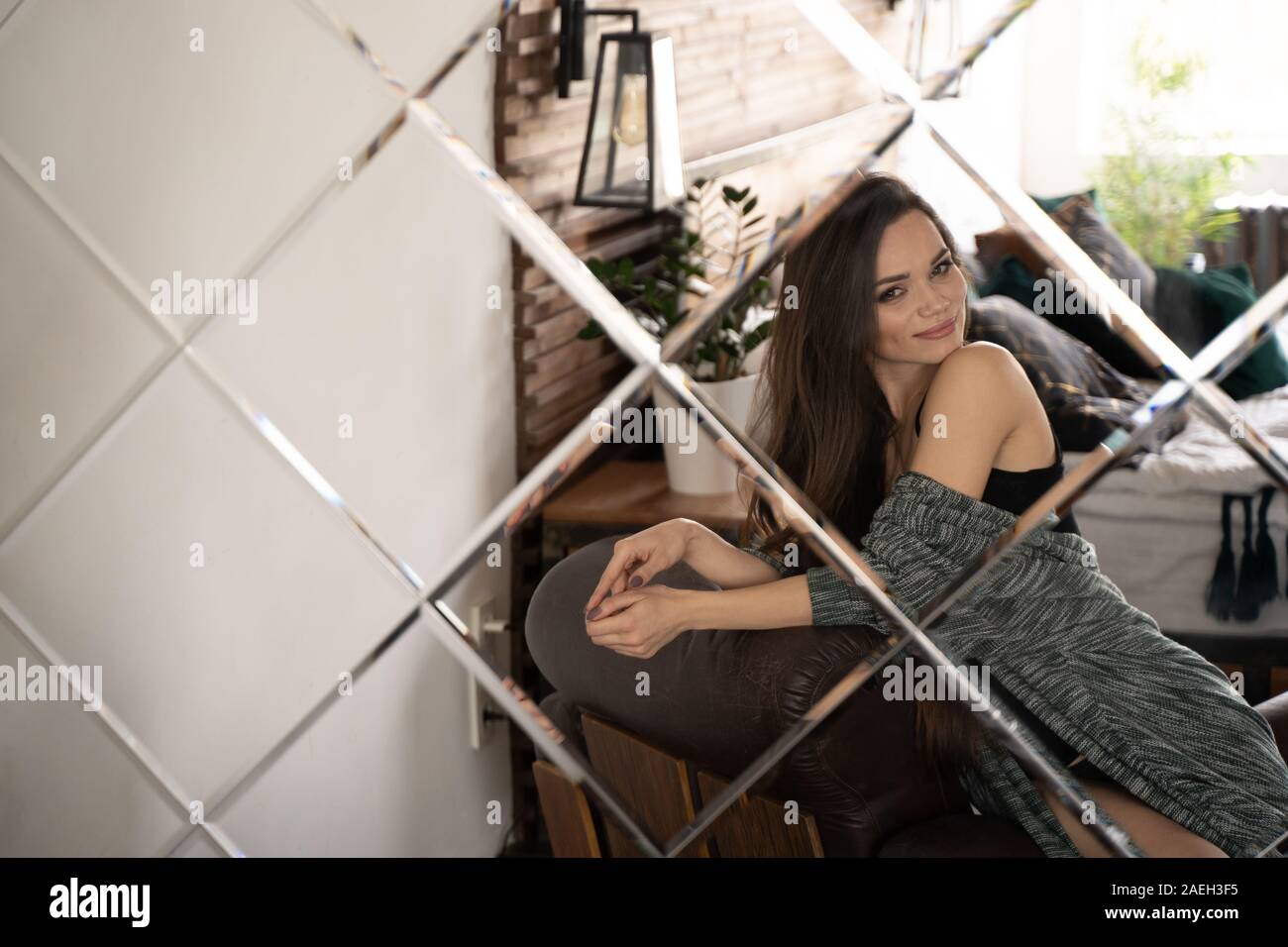 Woman sitting on leather armchair in front of mirror wall Stock Photo ...