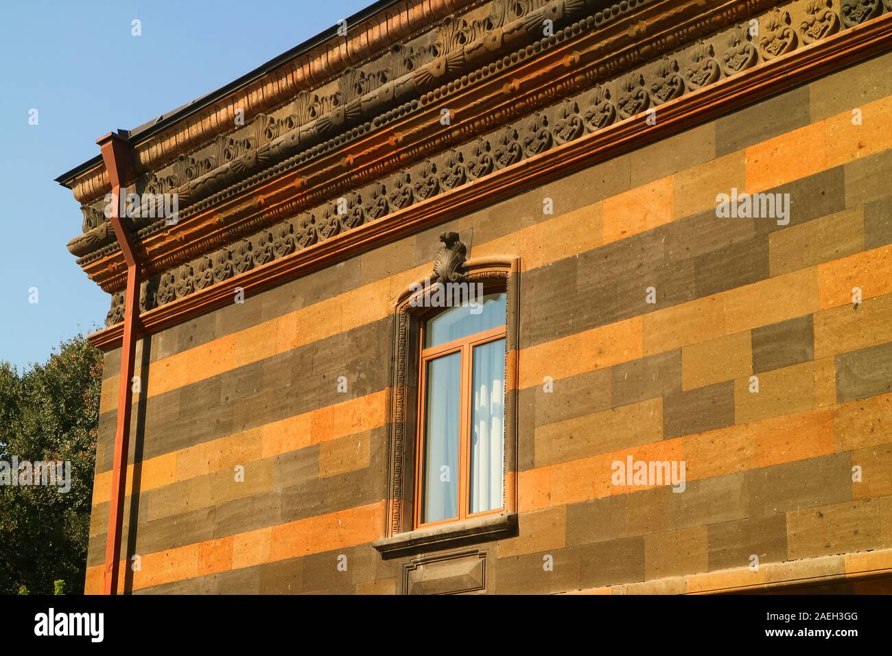 Closed decorative glass window on the facade of orange and brown stone ...