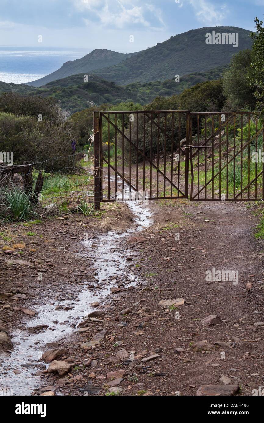 Fence with a gate and a pathway or road with a small river made by rain ...