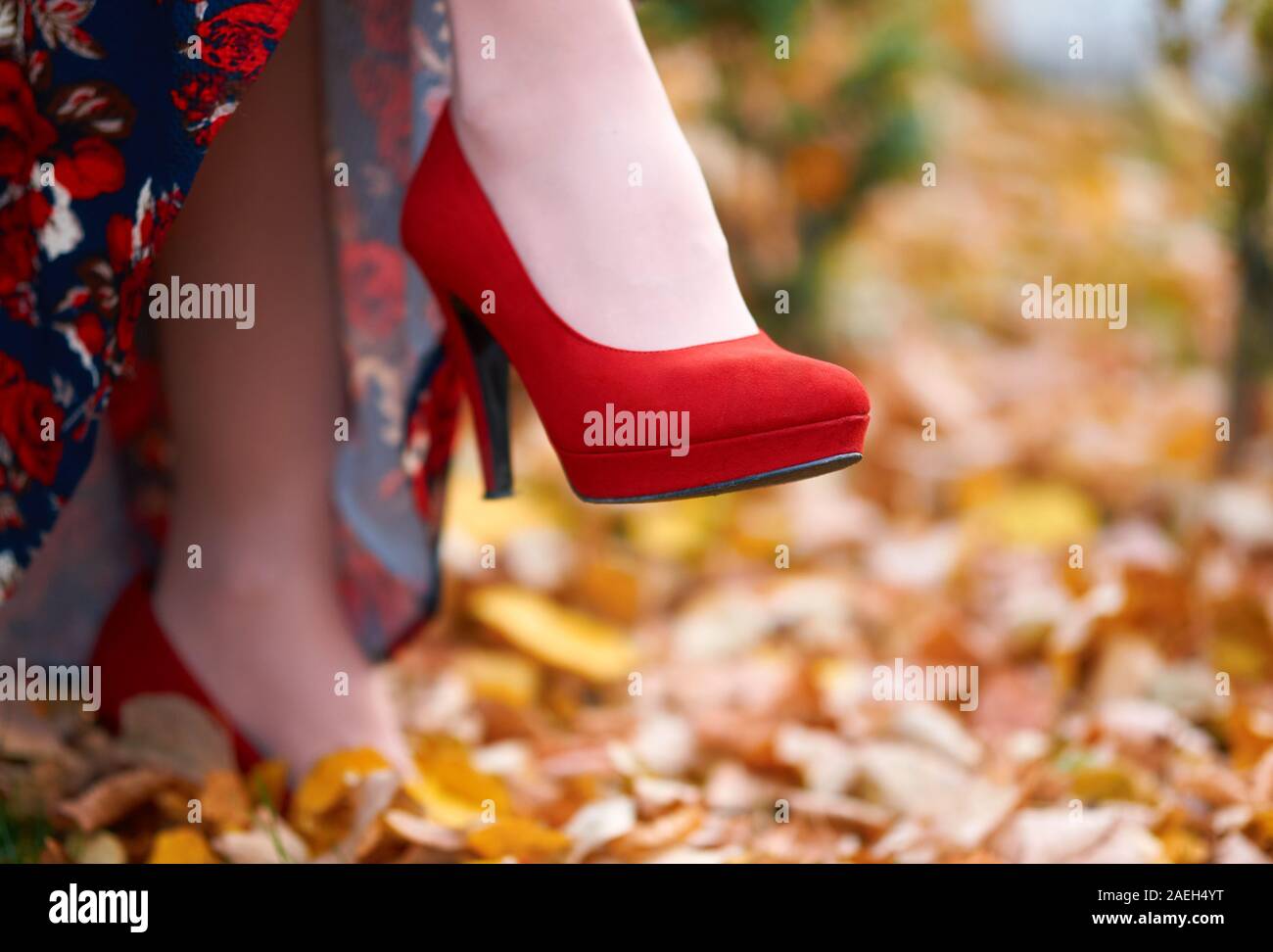 close up of women's feet shod in red high heels shoes, autumn season ...