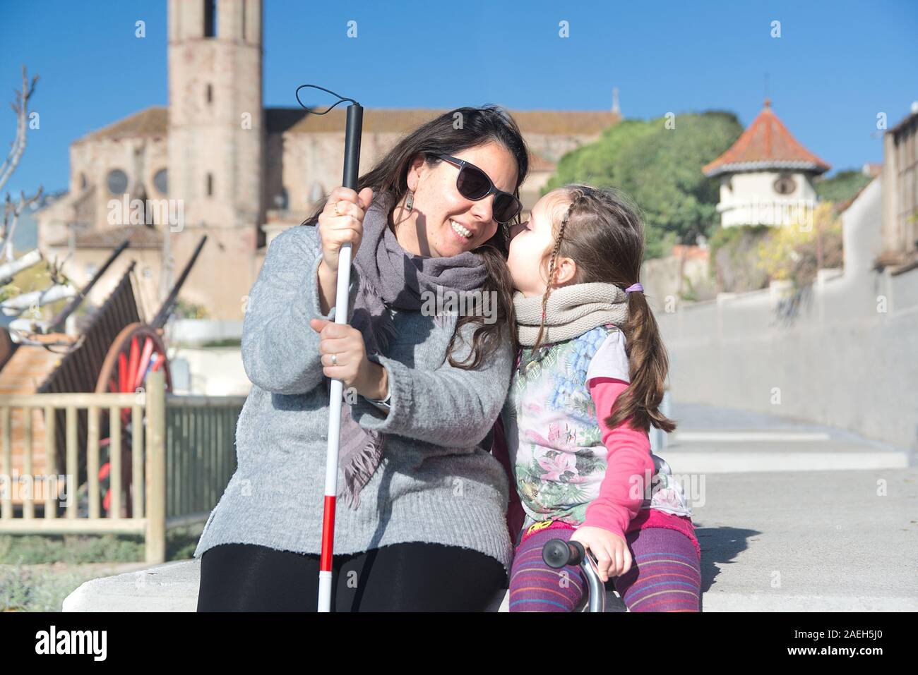 Blind mother with a white cane and her daughter talking sitting on a ...