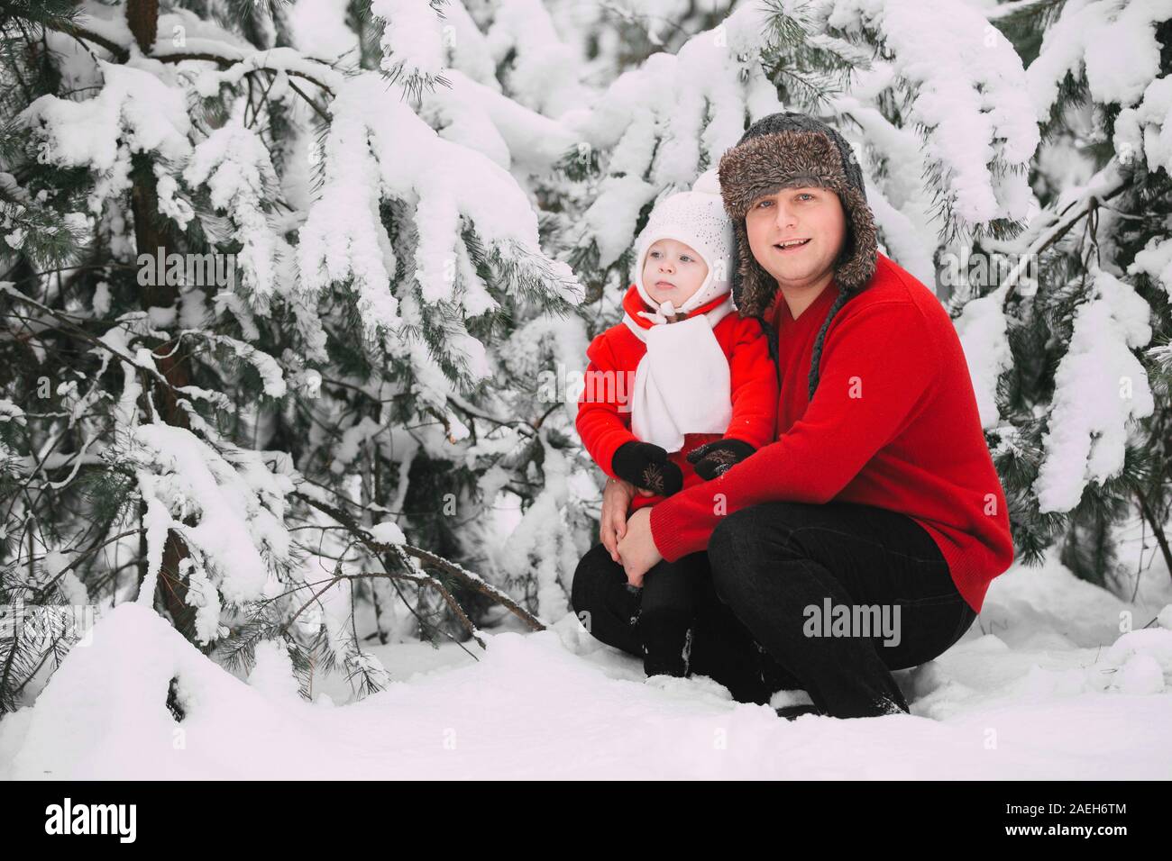 Portrait of happy little girl in red coat with dad having fun with snow in winter forest. girl ...