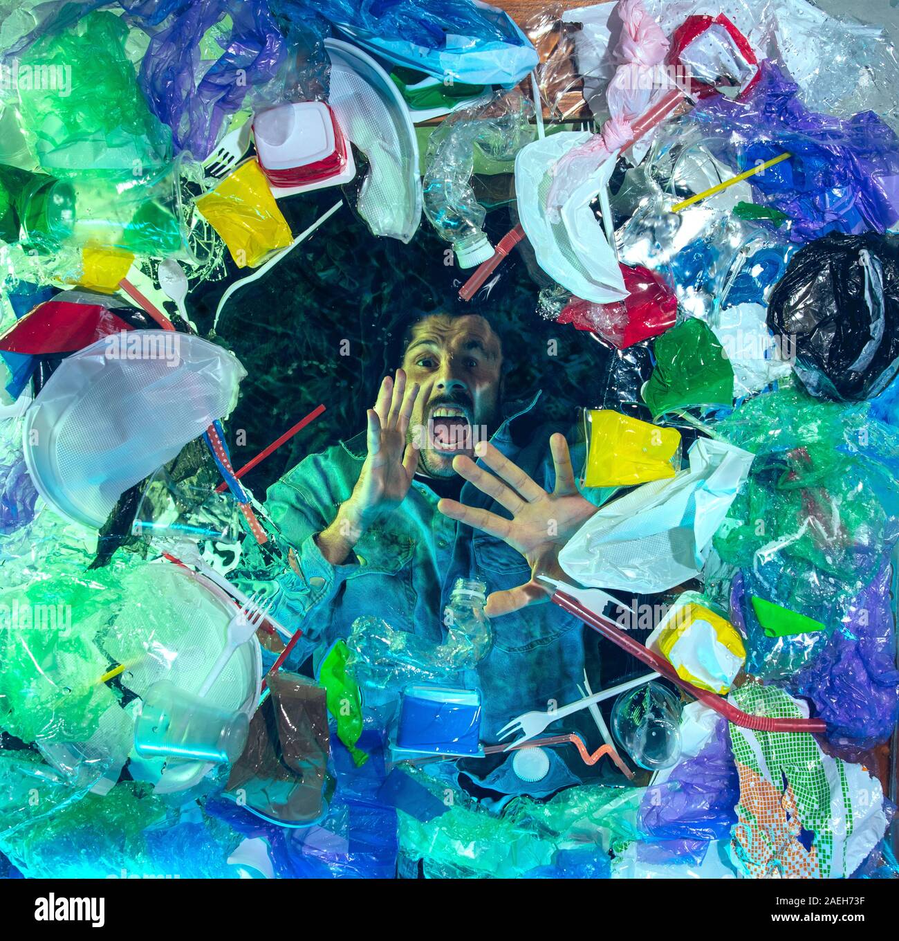 Man drowning in water under plastic recipients pile, garbage. Used ...