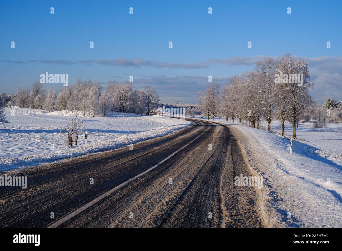 car tracks in the snow on the winter road in sunny day with frost on ...
