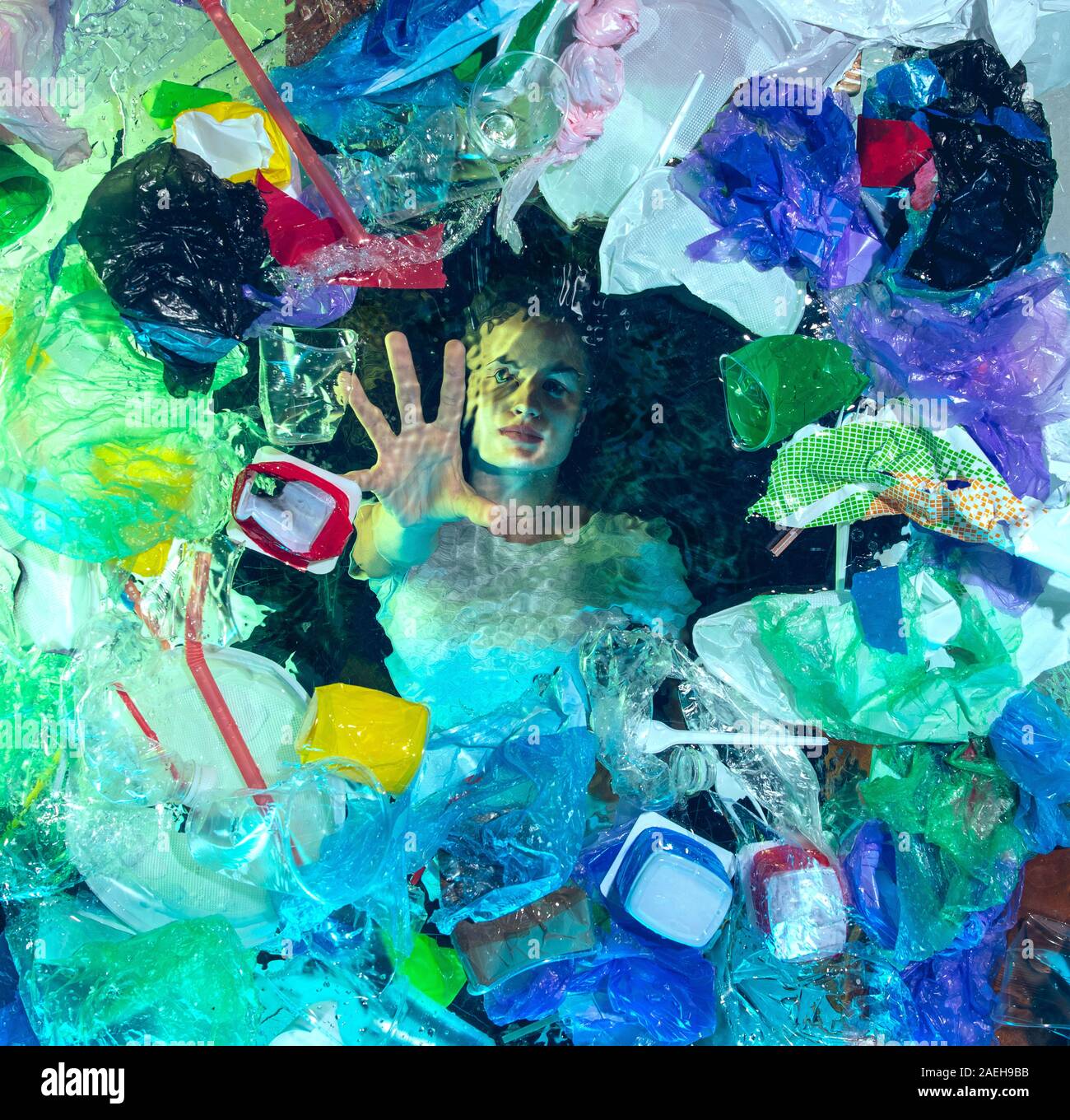 Woman drowning in water under plastic recipients pile, garbage. Used ...