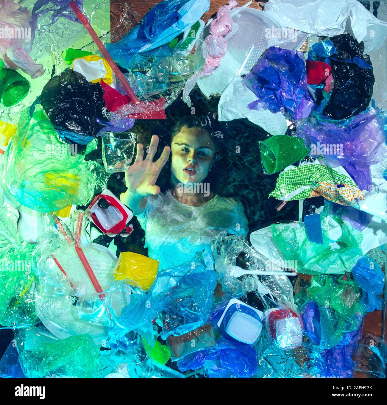 Woman drowning in water under plastic recipients pile, garbage. Used ...