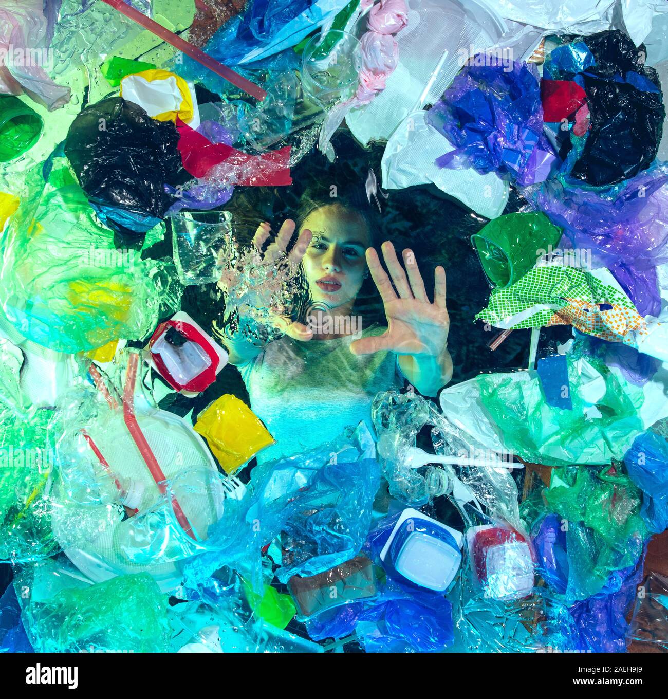 Woman drowning in water under plastic recipients pile, garbage. Used ...