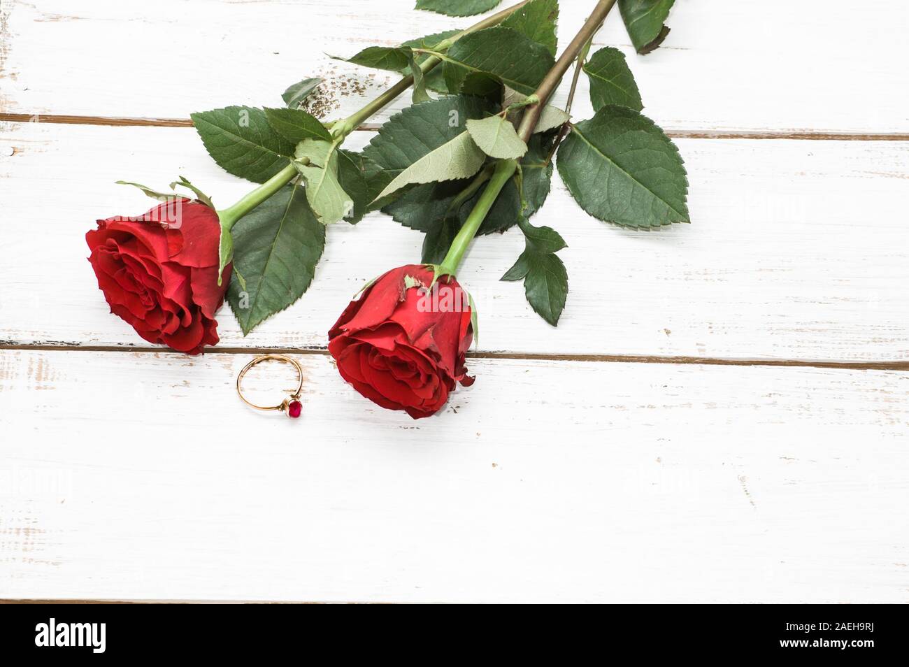 Red roses and engagement ring on wooden background, wedding invitation ...