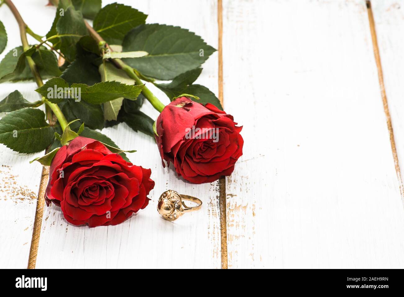 Red roses and engagement ring on wooden background, wedding invitation ...