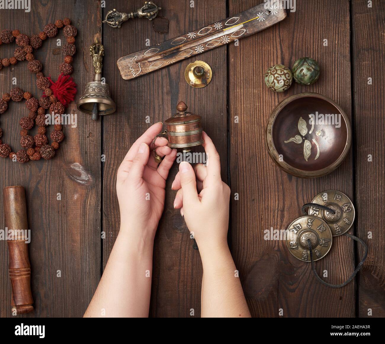 female hands hold a prayer drum on the wooden table, items for ...