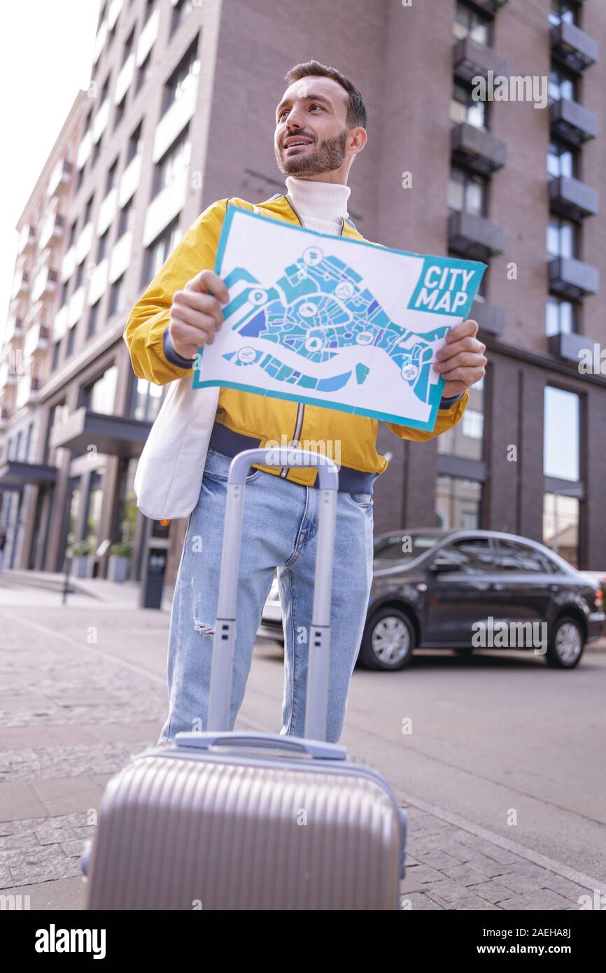 Positive delighted young man standing near suitcase Stock Photo - Alamy