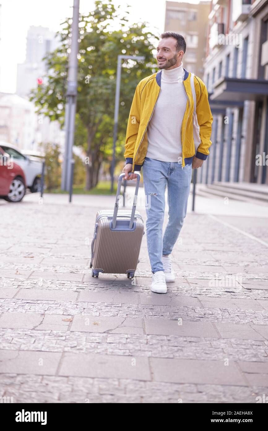 Handsome young male person wheeling his suitcase Stock Photo - Alamy
