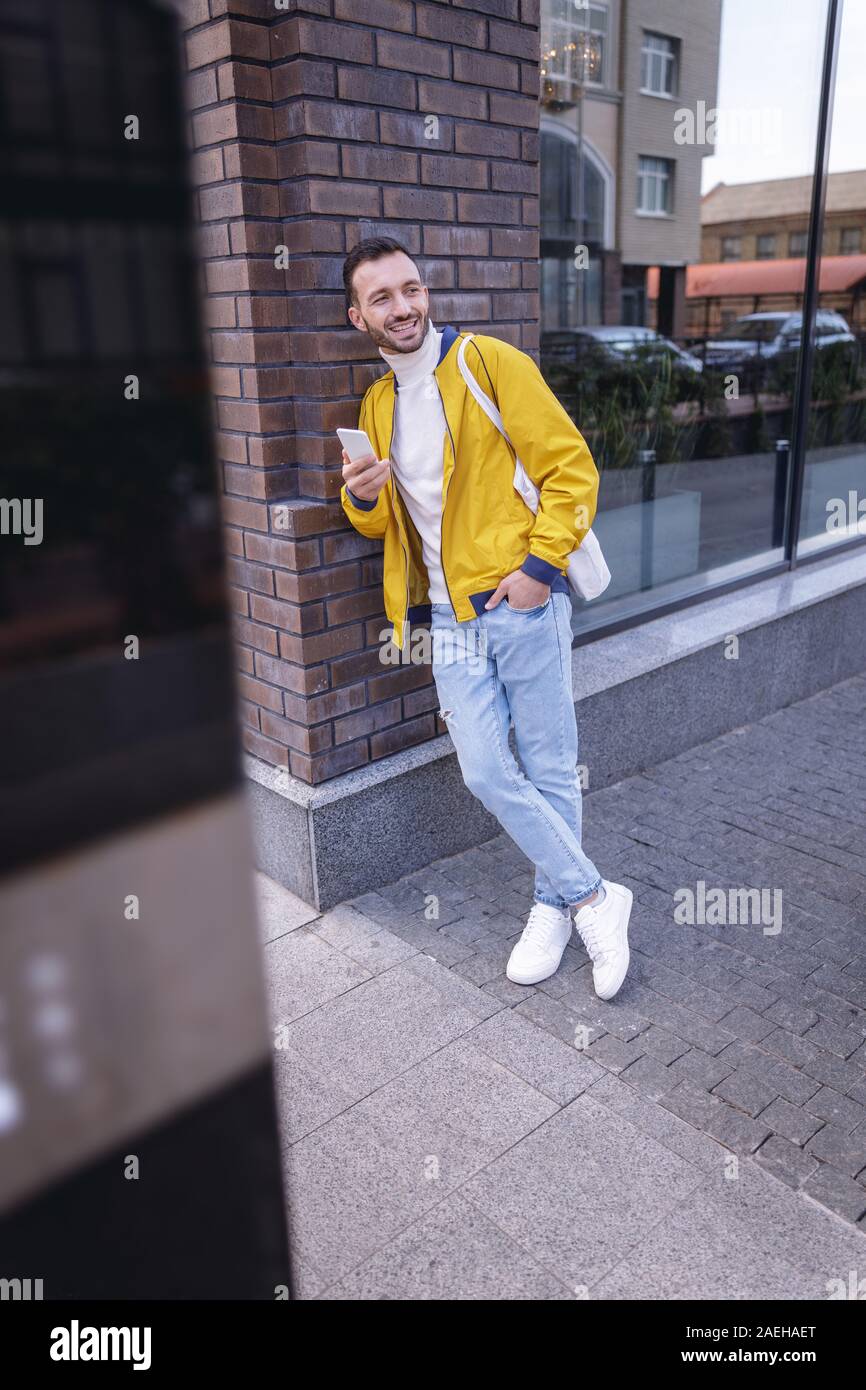 Positive delighted brunette man standing near building Stock Photo - Alamy