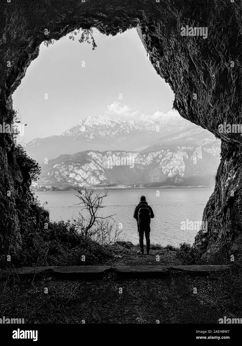 A man looking outside a cave in black and white Stock Photo - Alamy