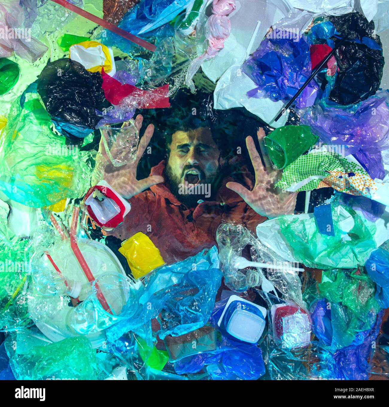 Man drowning in water under plastic recipients pile, garbage. Used ...