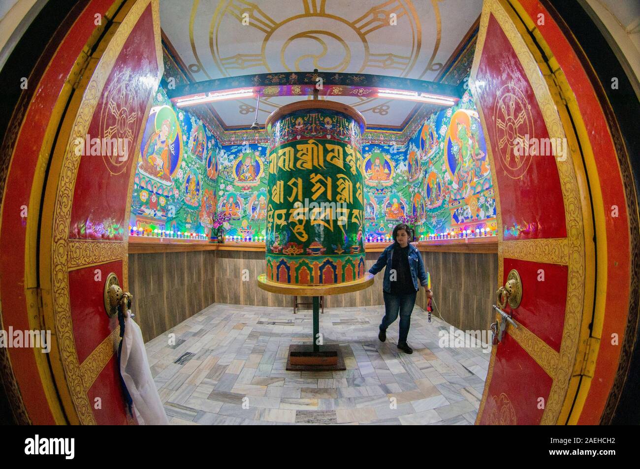 Beautiful huge bhuddhist prayer wheel with young girl crossing an ...