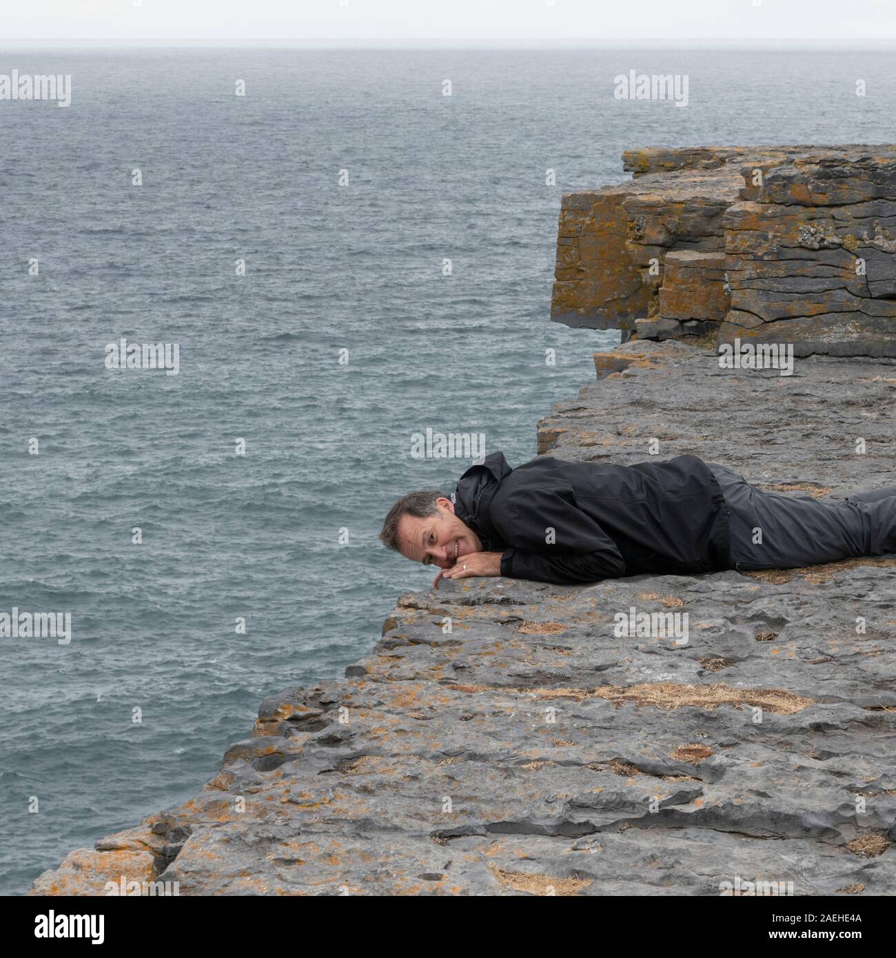 Man peeking over the edge of cliff, Dun Aengus, Inishmore, Inishmore ...