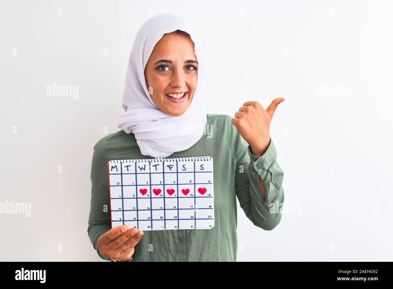 Young Arab woman wearing hijab showing menstruation calendar over ...