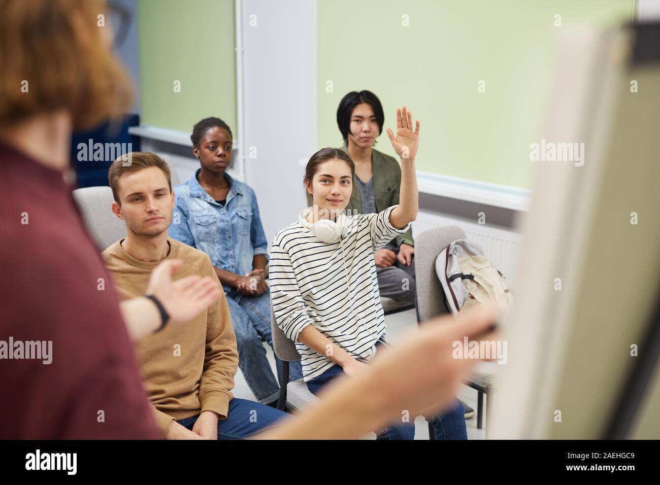 Group of young people sitting and listening to young man who standing ...