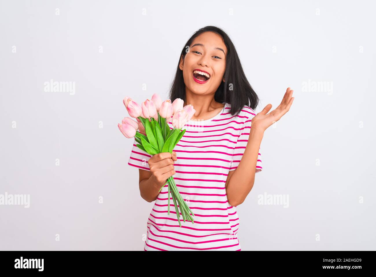 Young chinese woman holding bouquet of roses standing over isolated ...