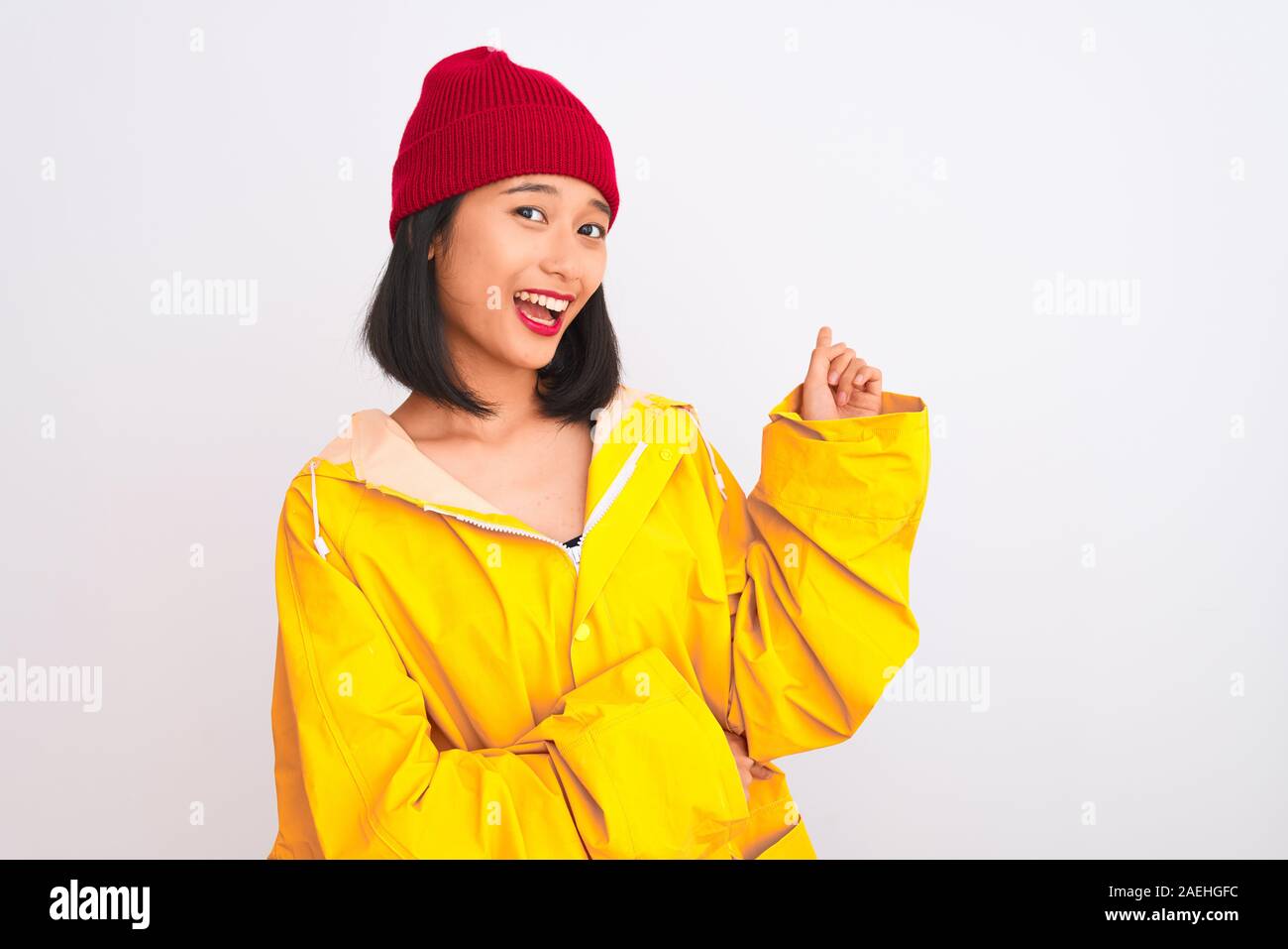 Young beautiful chinese woman wearing raincoat and wool cap over ...