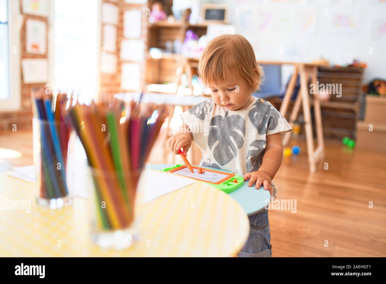 Adorable toddler drawing using digital board around lots of toys at ...