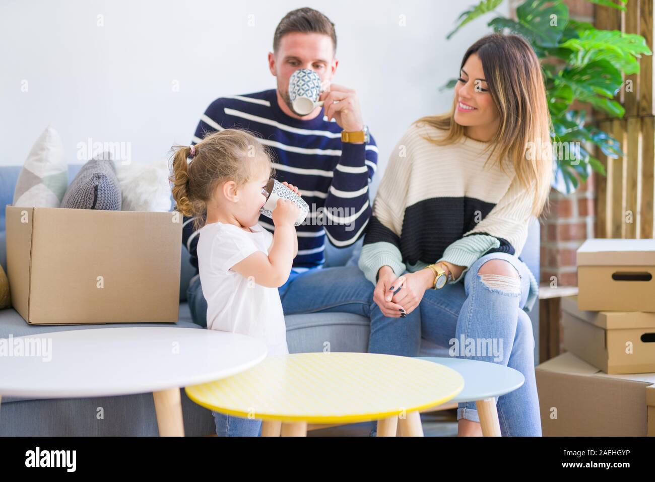 Beautiful family, parents sitting on the sofa drinking coffee looking ...