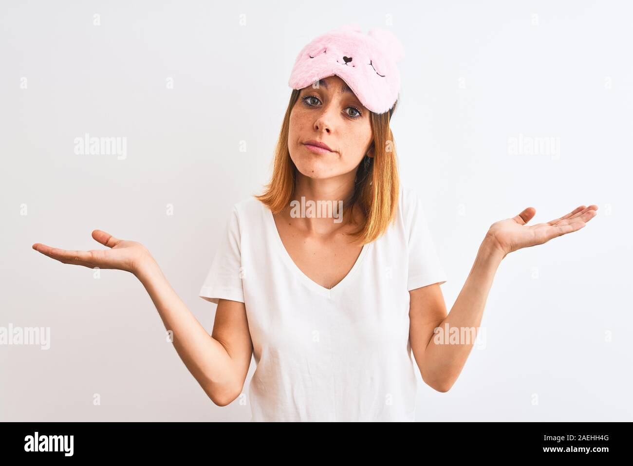 Beautiful redhead woman wearing sleeping mask over isolated background ...