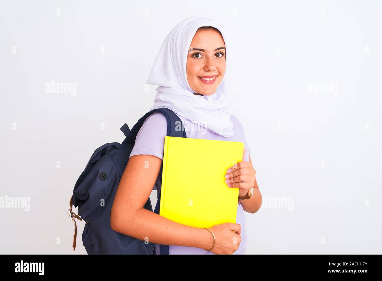 Arab student girl wearing hijab and backpack holding book over isolated ...