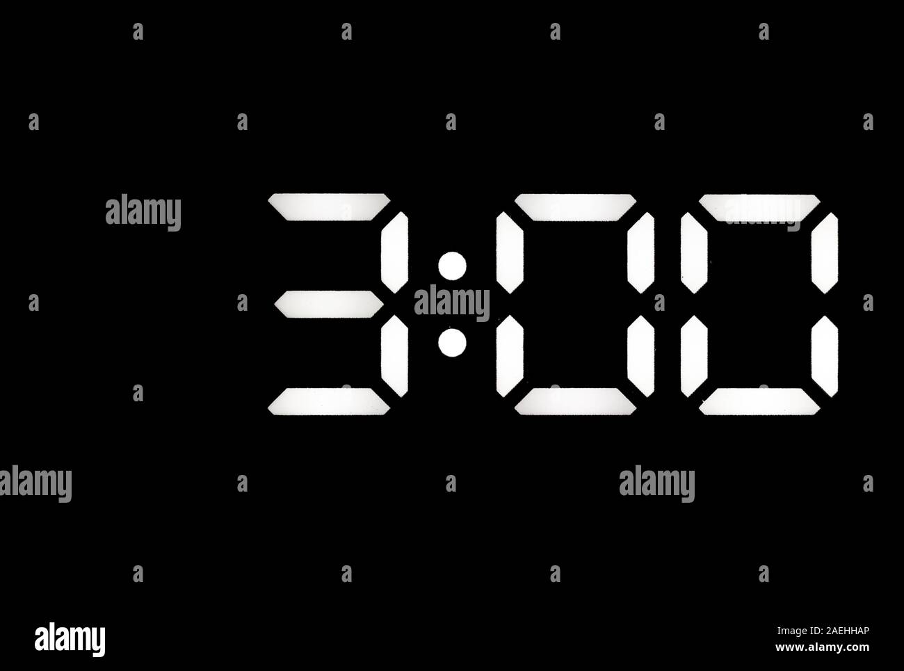Real white led digital clock on a black background showing time 3:00 ...
