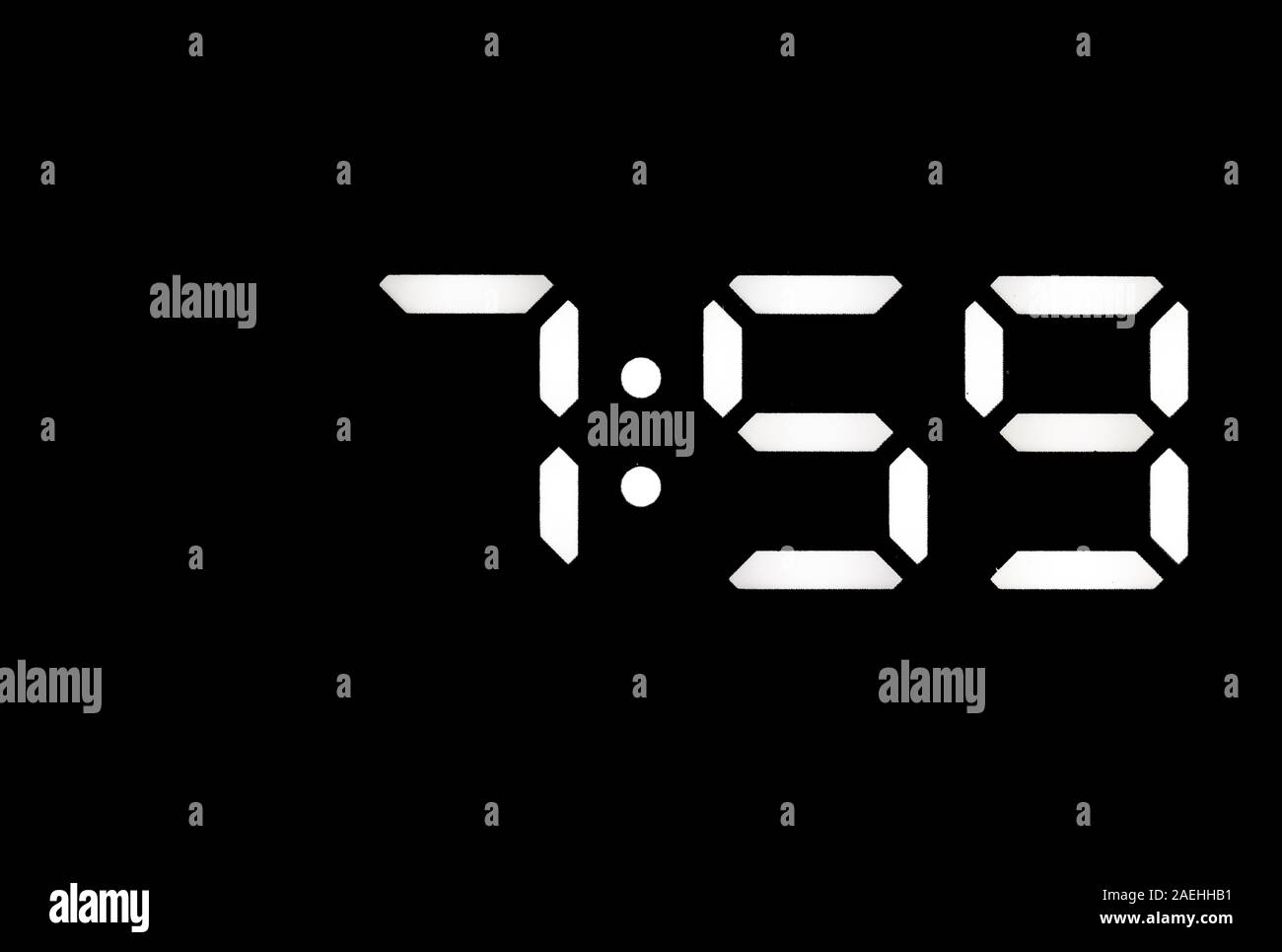 Real white led digital clock on a black background showing time 7:59 ...