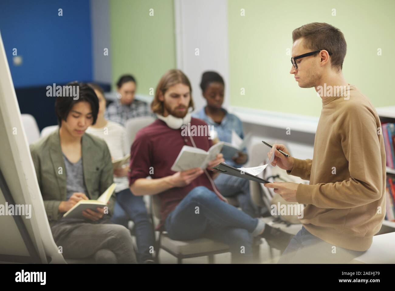 College student holding his report and presenting it to the audience ...