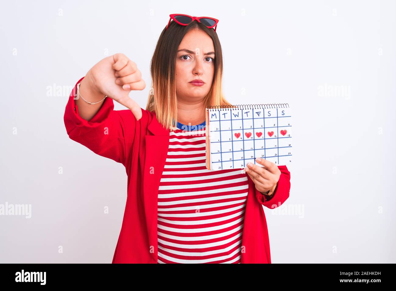 Young beautiful woman holding period calendar standing over isolated ...