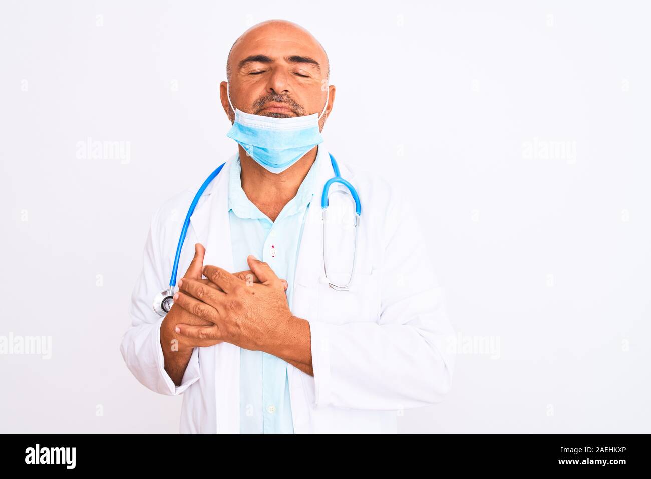 Middle age doctor man wearing stethoscope and mask over isolated white ...
