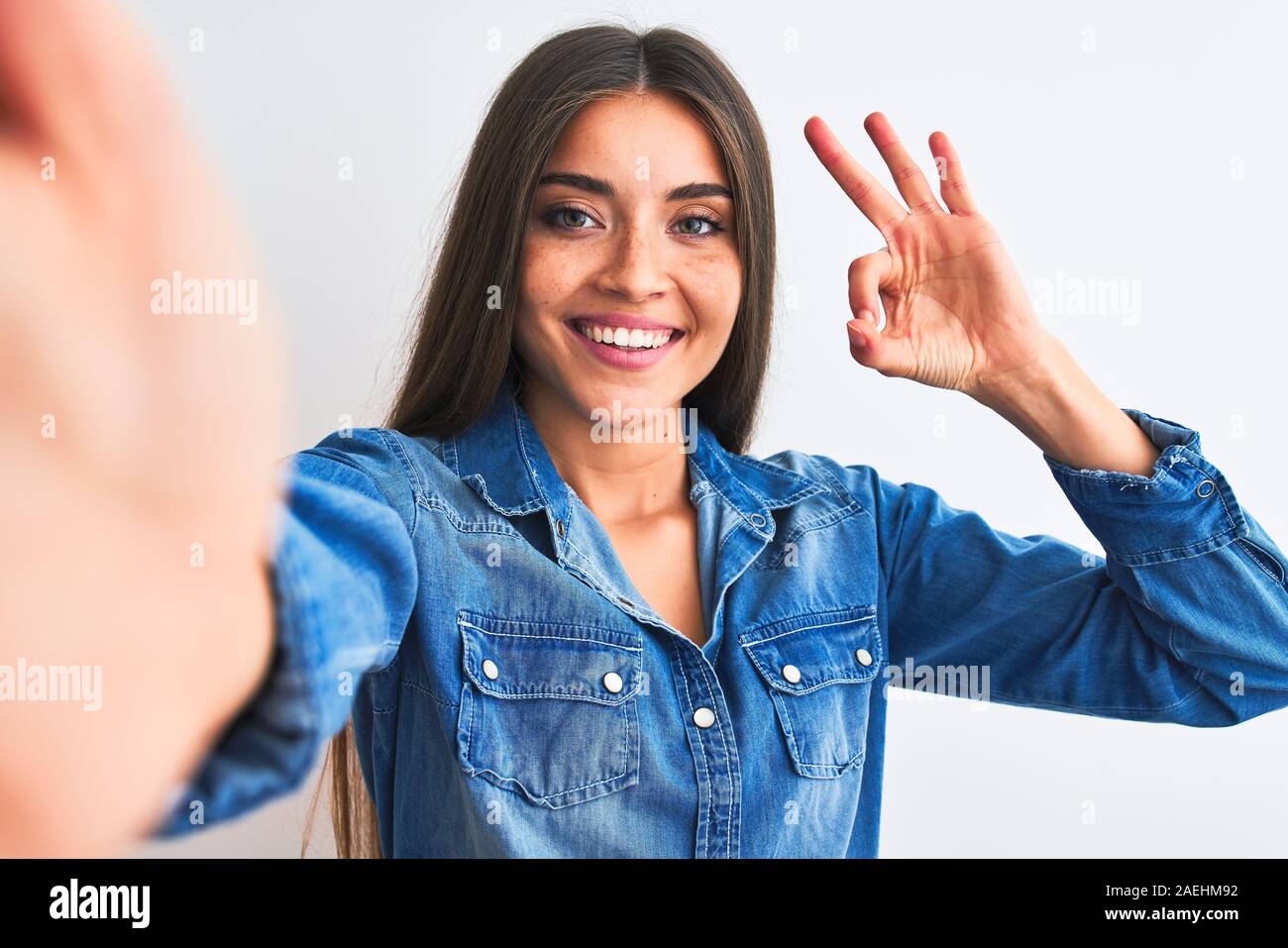 Beautiful woman wearing denim shirt make selfie by camera over isolated ...