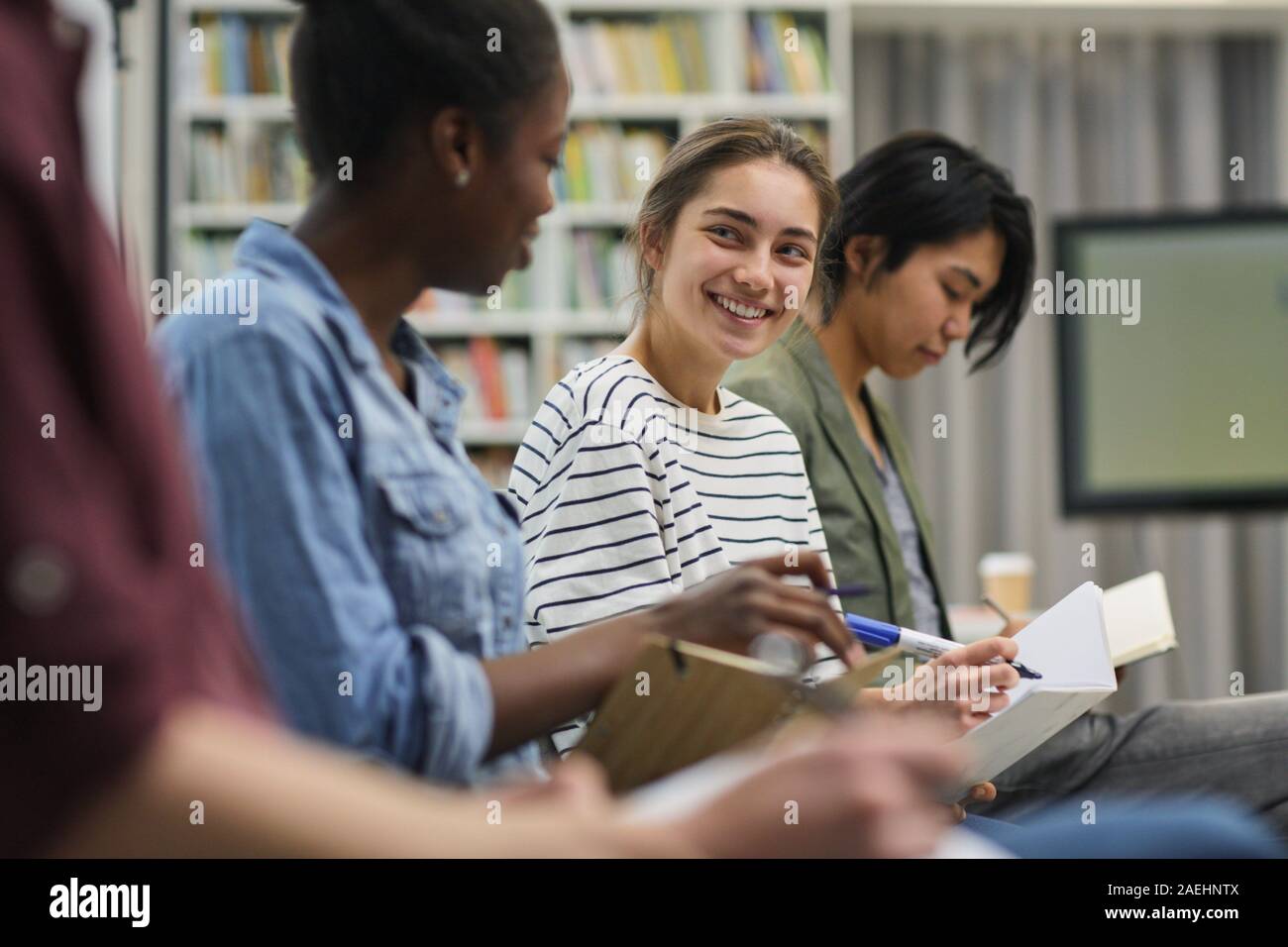 Group of students sitting and talking to each other while writing ...