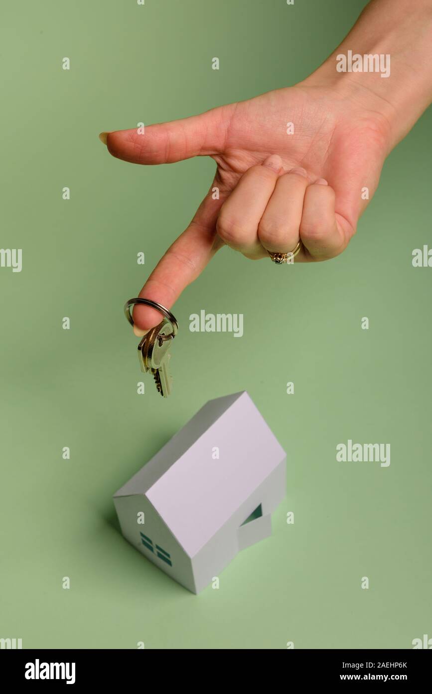 White family paper house. House keys in hand on mint background paper ...