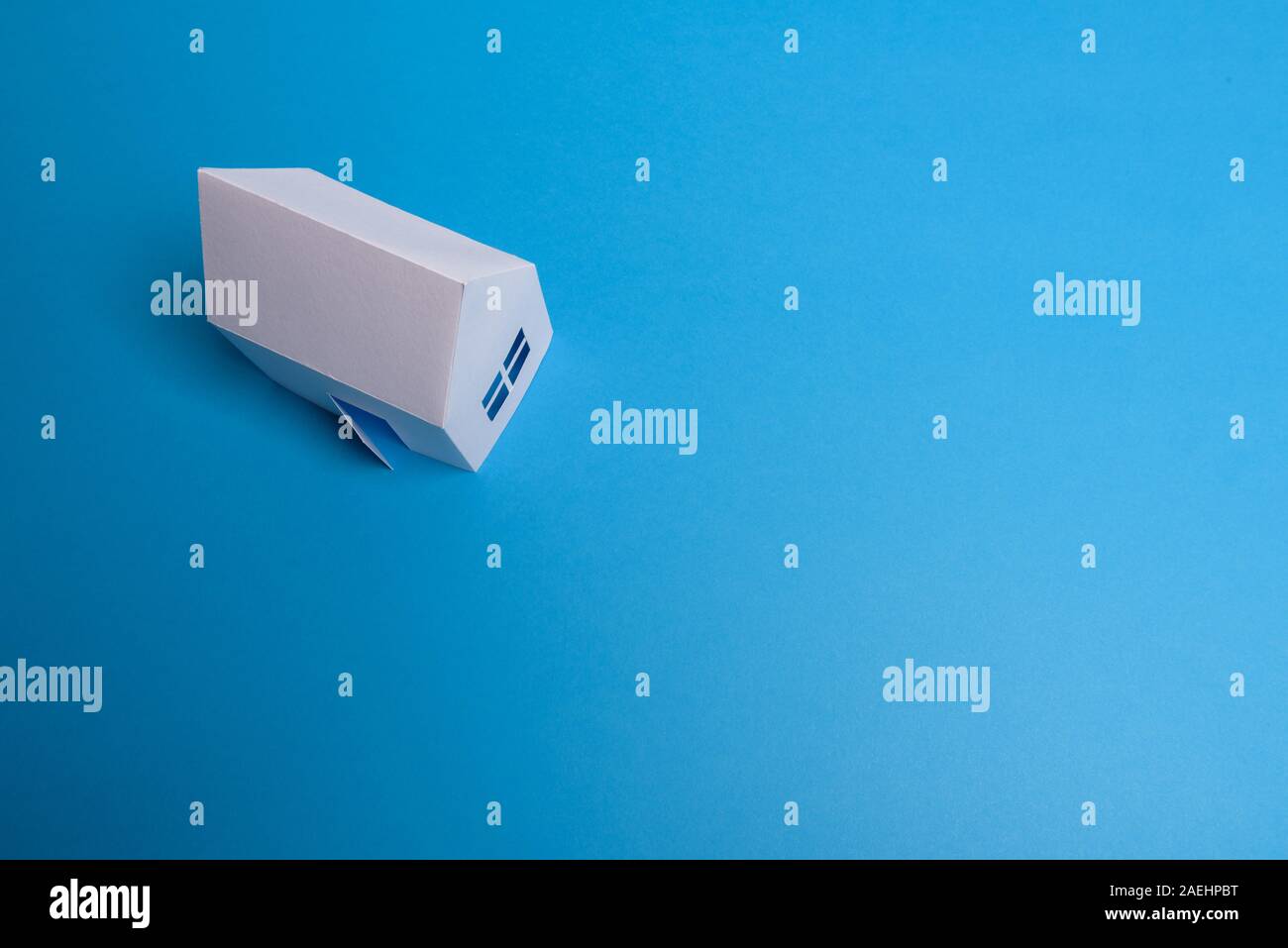 White family paper house over block of flats on blue background paper ...