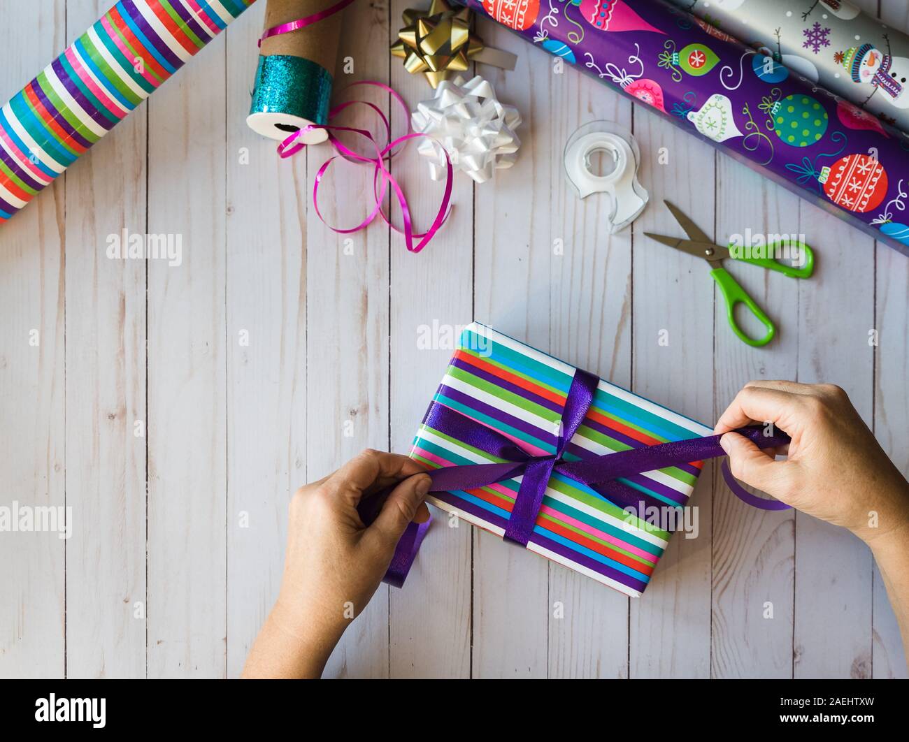 Hands wrapping present with gift wrap supplies on white table Stock ...