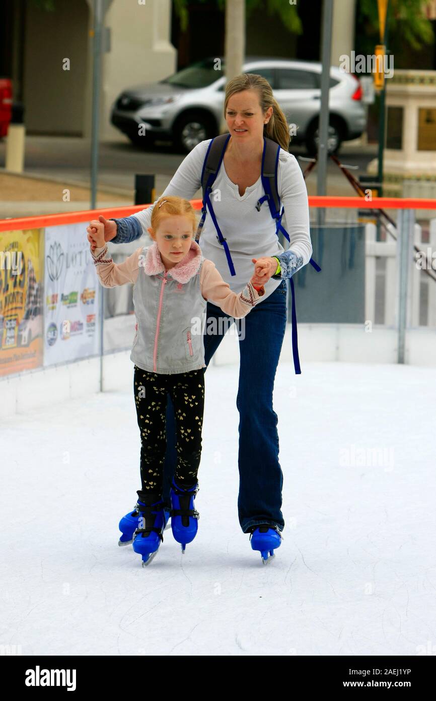 Mother and young daughter enjoying the outdoor ice skating rink in ...