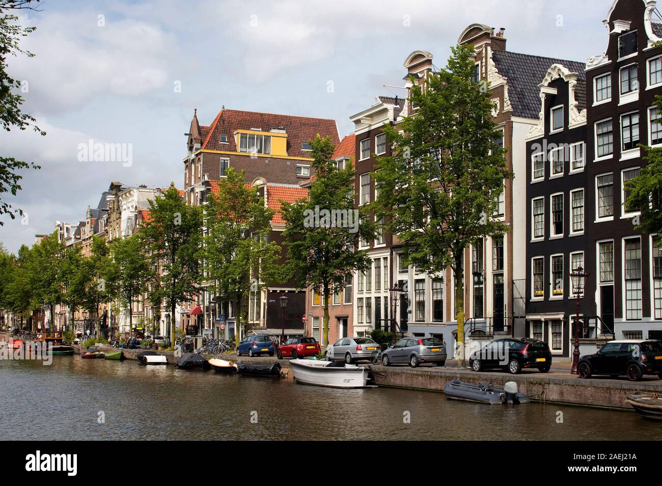 View of canal, parked boats, cars, trees and historical, traditional ...